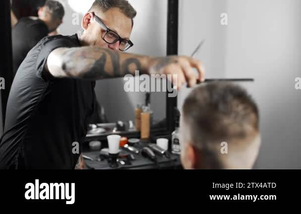 Tattoed barber makes haircut for customer at the barber shop, mans ...