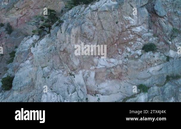 Steep cliff with ledges. Shot. Top view of rocky steep wall with sparse ...