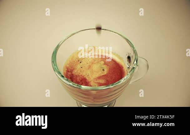 coffee drop falling in slow motion inside of trasparent cup of espresso ...
