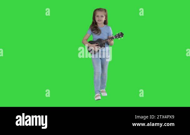 Little girl singing and playing small guitar while walking towards ...