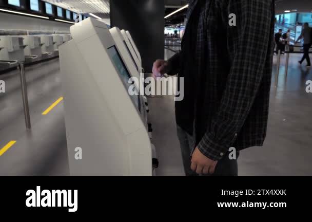 Man using the check-in machine at the airport getting the boarding pass ...