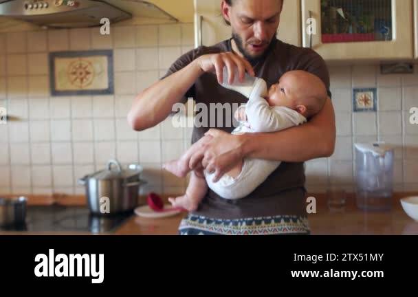 Father Is Giving Baby Bottle To His Son. Young single father in the ...