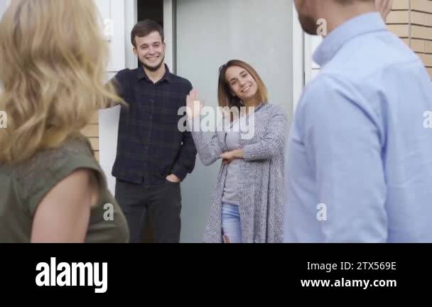 Married couple leaving home of they friends waving hands. Friendly ...
