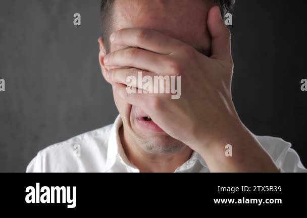 Young man in despair crying covering his face with his hand ...