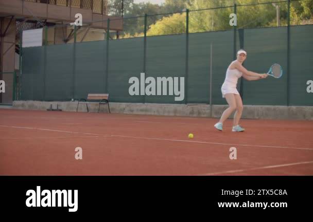 Professional equipped female beating hard the tennis ball with tennis ...