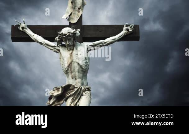 Crucifixion. Christian cross with crucified Jesus Christ statue over dark clouds time lapse ...