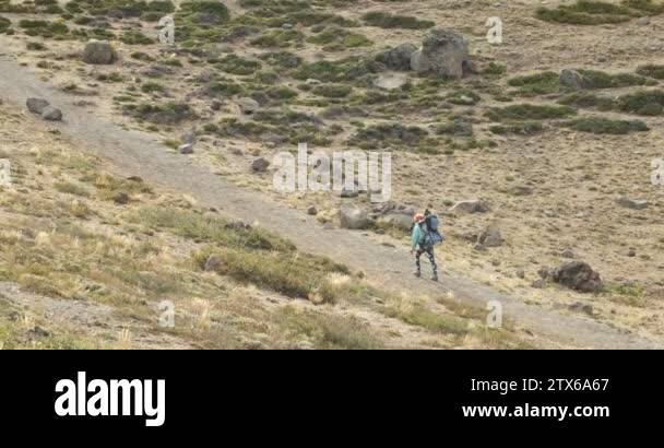Trekking in Batea Mahuida volcano. Lady carrying baby walking up the ...