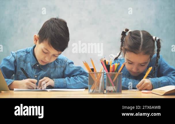Schoolkids, brother and sister, sitting at the table, writing, then ...