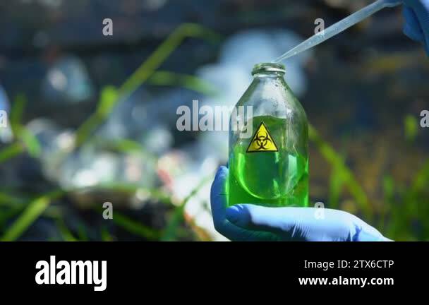 Scientist taking sample from bottle with biohazard sign against ...