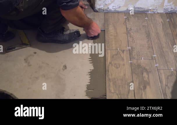 laying tile on the floor, ceramic tile laying, pressing down and ...