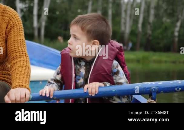 Little boy holding paddle on wooden boat. Funny child sits in boat and ...
