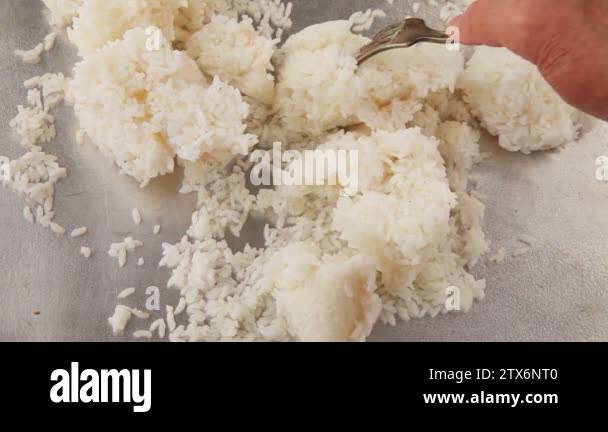 Using a fork, a woman separates cold rice clumps Stock Video Footage ...
