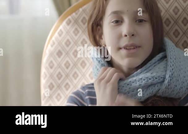 Portrait of the positive teenage girl taking off the warm blue scarf ...