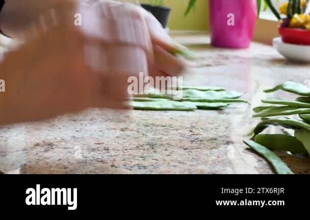 Cutting beans in a kitchen. A person removes pieces of the vegetable ...