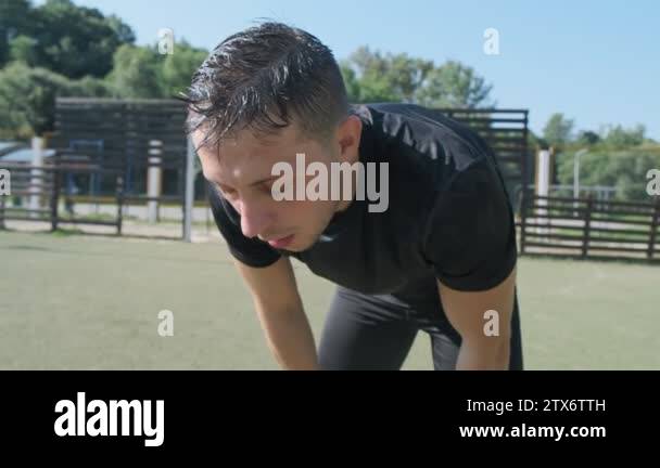 Exhausted bend young man looks into camera and rests after workout. He ...