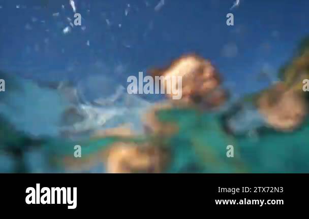 Beautiful woman sitting underneath a water fountain in swimming pool ...