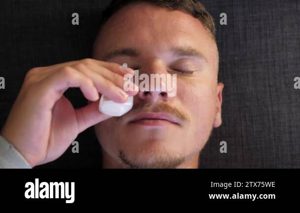 Close-up view of man who applying eye drop medicine healing. Young guy ...
