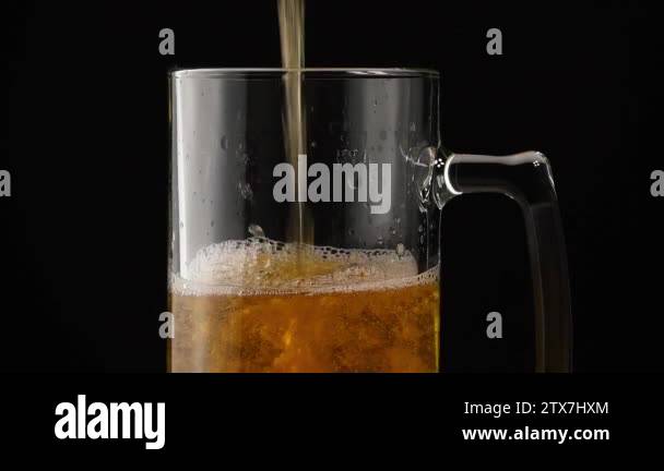 Close up background of pouring lager beer with bubbles and froth in ...