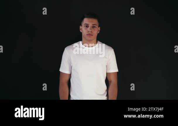 Guy with neutral emotions stands and looks on camera. Suddenly he ...