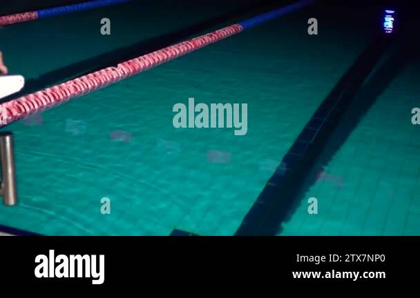 Unrecognizable male swimmer jumps off starting block and start swims in ...