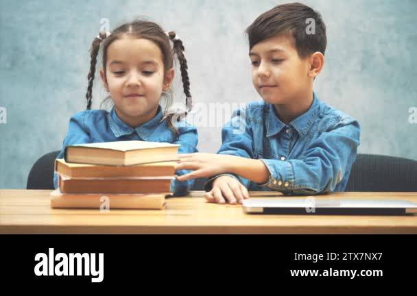 Two kids choosing between stack of books and laptop. Laptop is the ...