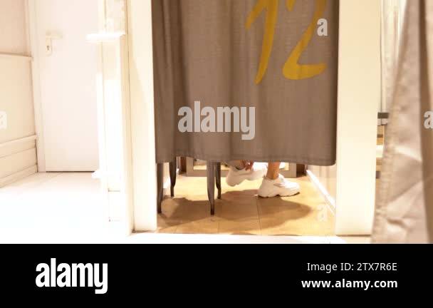 female legs are visible from under the curtains in the fitting room of ...