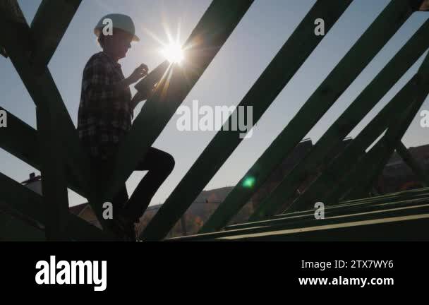 Silhouette of an engineer, works among the rafters of the roof, uses a ...