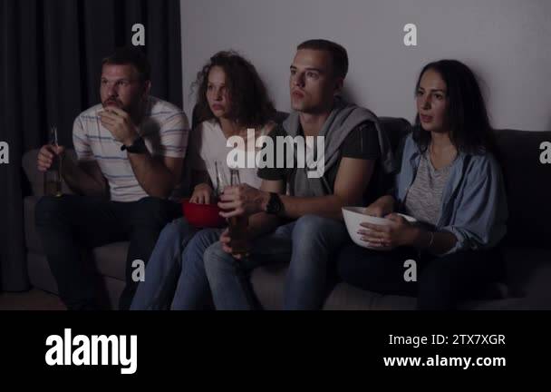 Four friends eating popcorn, drinking beer watch horror movie together ...