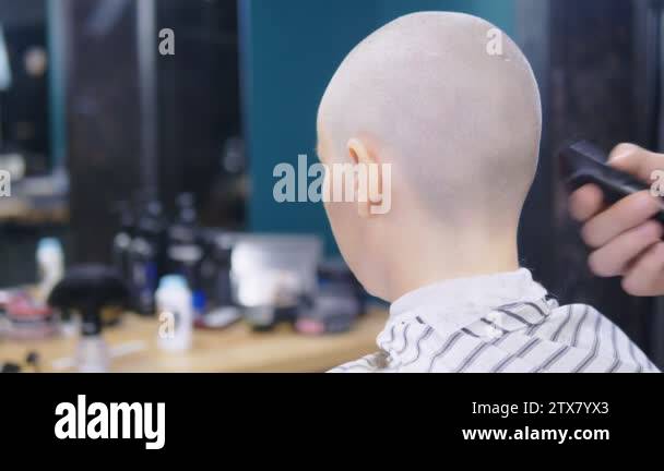 concept of hair loss after chemotherapy. the hairdresser shaves the ...