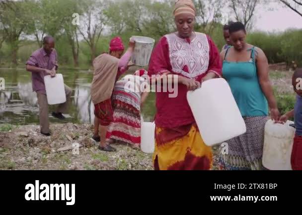 African villagers at river fill containers with as much water as they ...