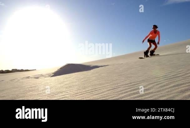 Woman performing a jump while sand boarding in the desert 4k Stock ...