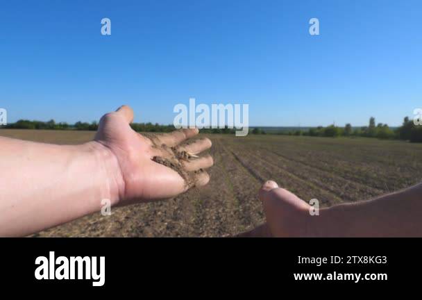 Male farmer hands holds a handful of dry ground and checks soil ...