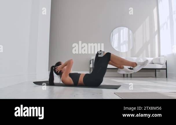 Young girl doing bicycle crunches exercise, working out at home. Young ...