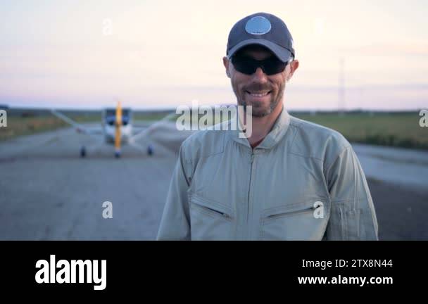 Pilot stands on a airplane background and smiles at camera. Portrait of ...