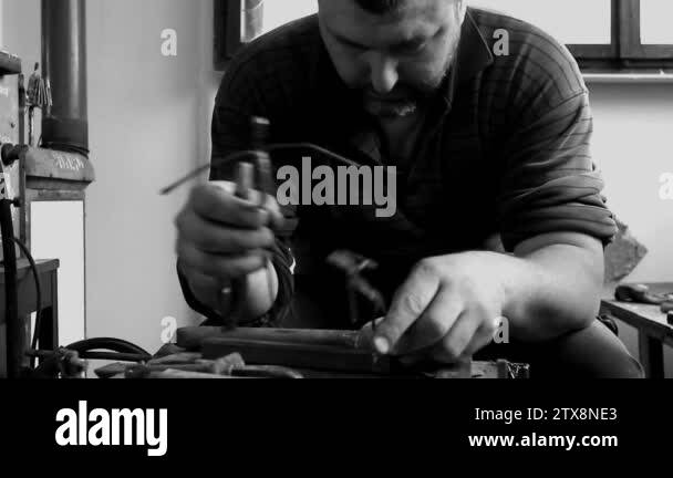 Craftsman is making figure with metal wire in his workshop. Artist is ...