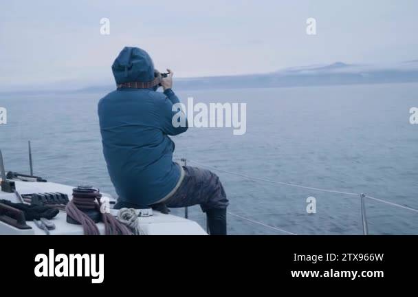 Man making photo of landscape during sea voyage on sailing ship back ...