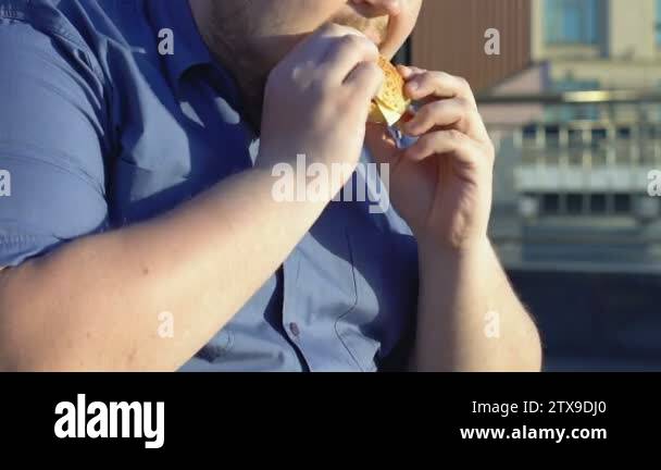 Plump male office worker chewing fatty burger outdoors, plus size ...