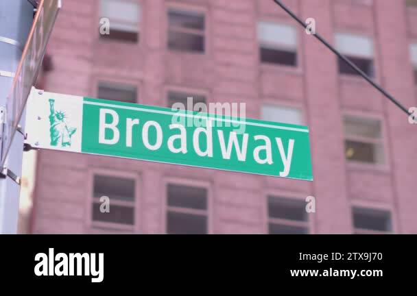 CLOSE UP: Lit Broadway traffic sign mounted on a pole on a sidewalk at ...