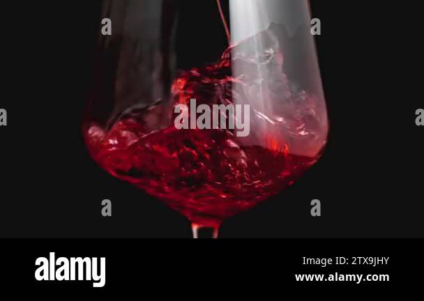 Red wine forms beautiful wave. Wine pouring in wine glass over black ...