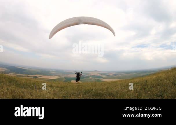medium shot professional paraglider pilot prepares for takeoff raises ...