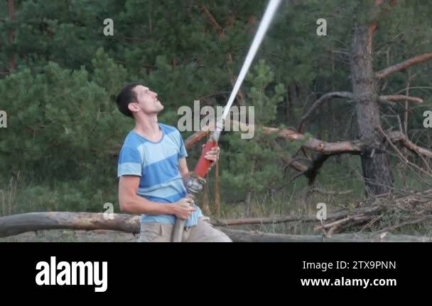 Man holds a fire hydrant in his hands with a big water jet directed ...