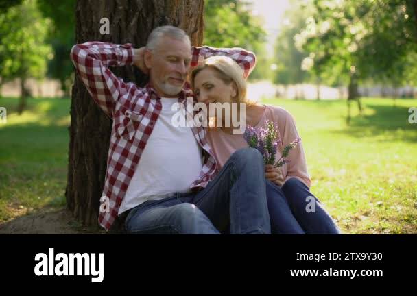 Romantic date of two retired people, man hugging wife with flower ...