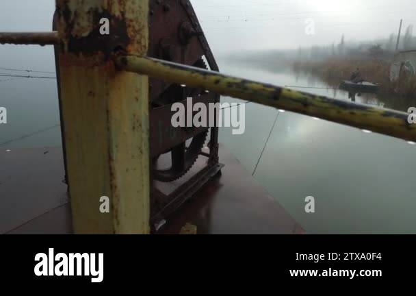 Metal floating bridge over river, early in morning with fog and dew ...