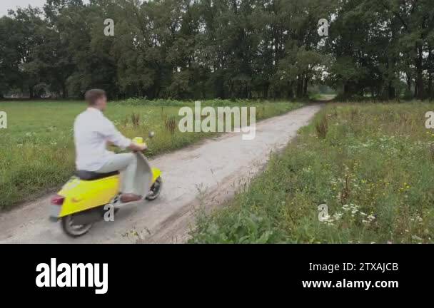 Handsome guy riding his scooter outdoors. Young guy on a motorbike on a ...