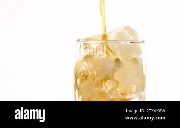 Extreme close up of pouring carbonated cola soft drink in transparent glass with ice cubes until ...