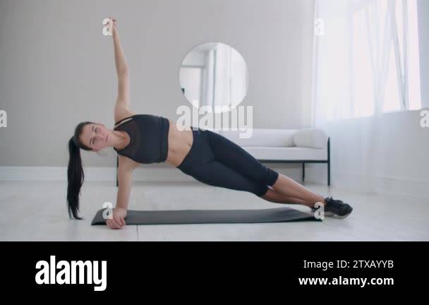 The brunette in the apartment does an exercise plank while standing in a static position on the ...