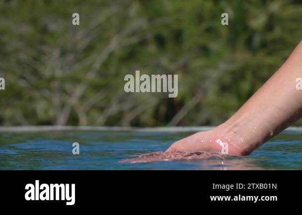 SLOW MOTION CLOSE UP: Caucasian female hand playing with water ...