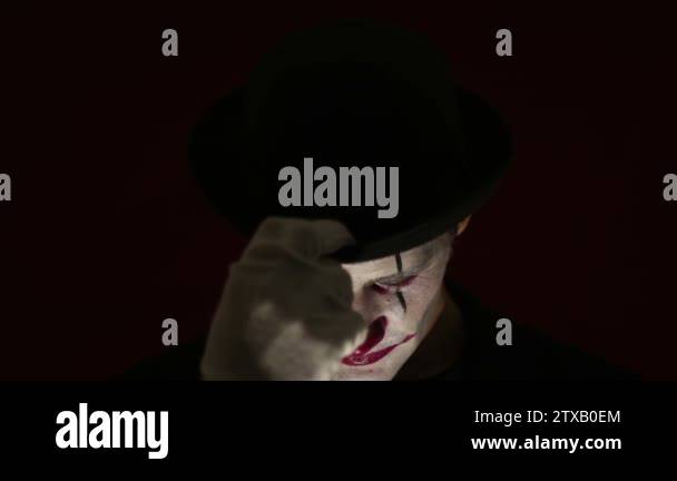 Terrible man in a clown makeup takes off his hat by welcoming his ...