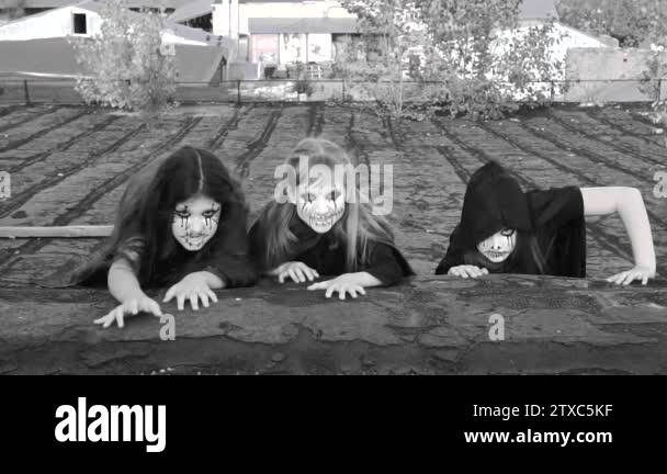 Three little teenage girls in zombie costumes crawl along the roof of ...