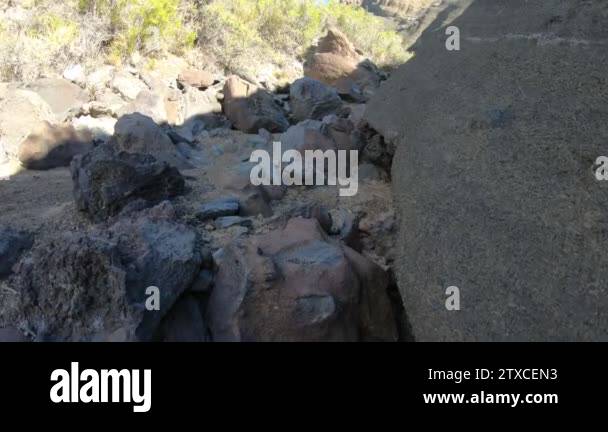 Walking along volcano malacara grey debris, dry river of vocanic depositions. Detail of grey ...